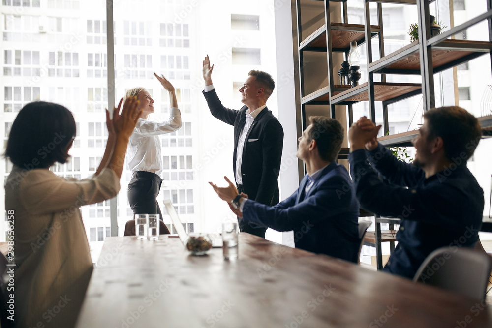 man congratulating his colleague with promotion, cheeful office workers ...