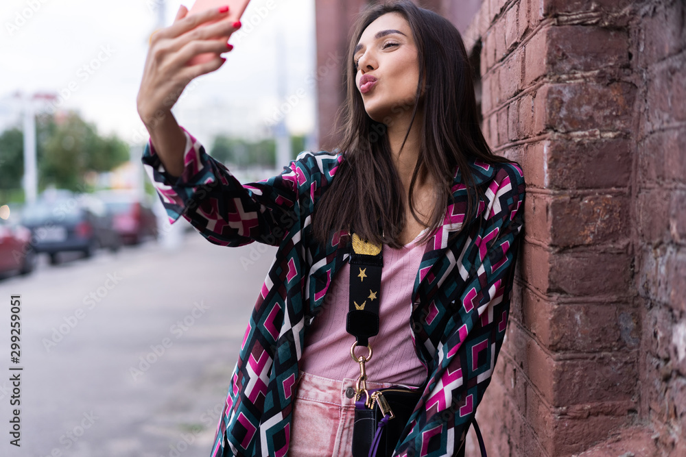 Sexy carefree girl posing in the street near wall. Taking selfie self ...