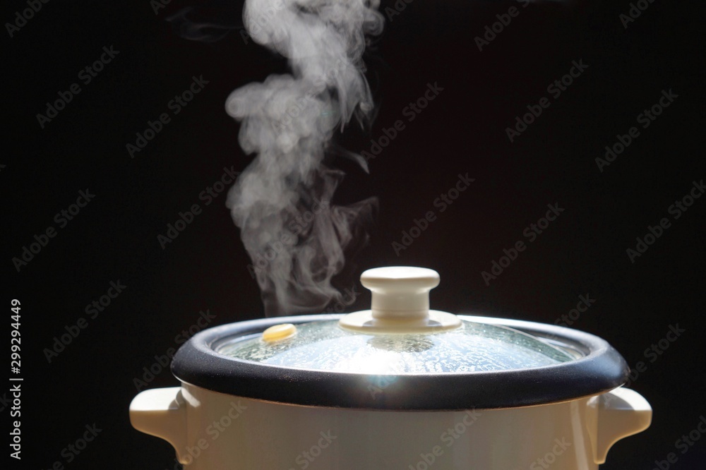 hot cooked rice in electric rice cooker with steaming on dark ...