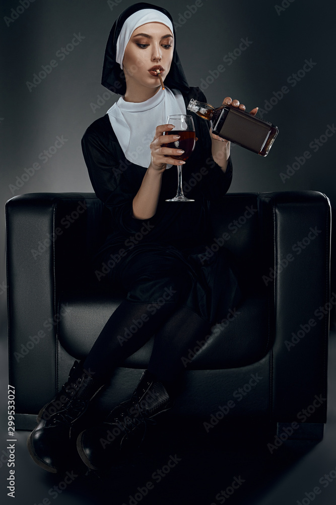 Stockfoto Full length shot of a nun, sitting on a chair. She's wearing ...