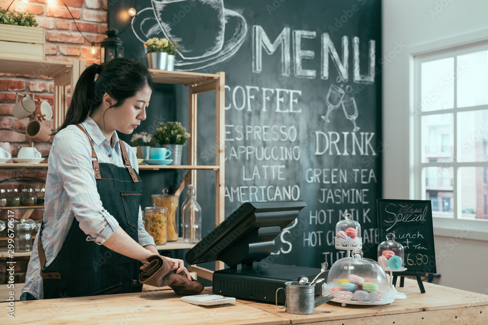Portrait of young cafe owner lady using cloth to wipe everything before ...