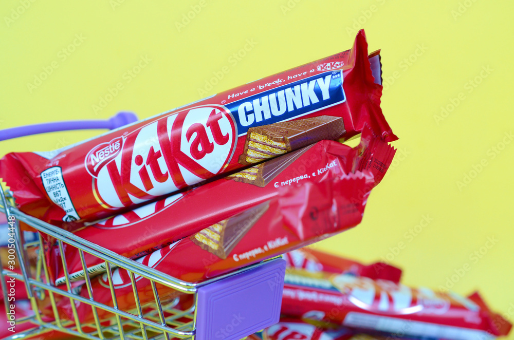 Kit Kat chocolate bars in small shopping cart on yellow background. Kit ...