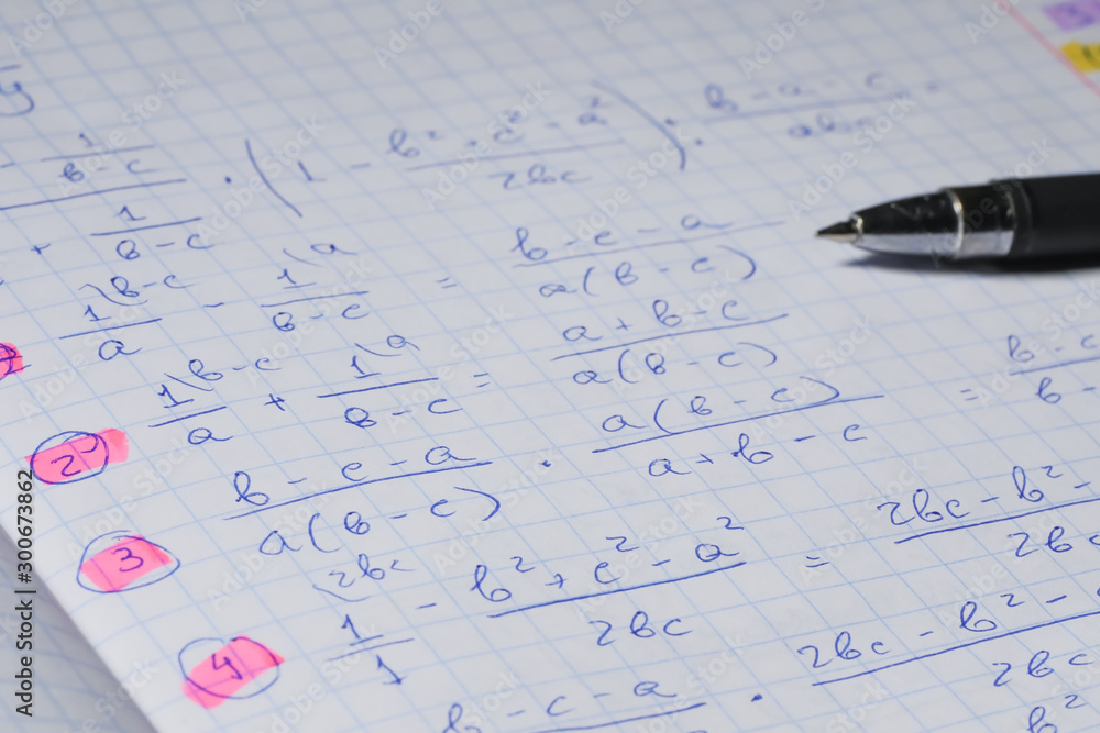 Algebraic calculations in open graph notebook with black pen. White ...