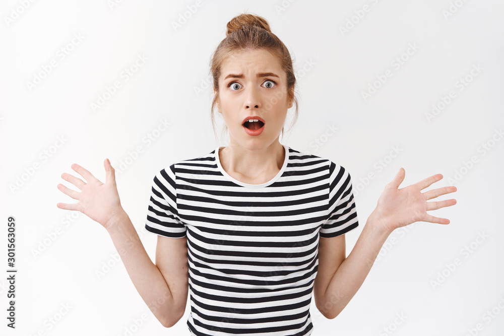 Concerned and shocked young caucasian girl with combed hair in bun ...