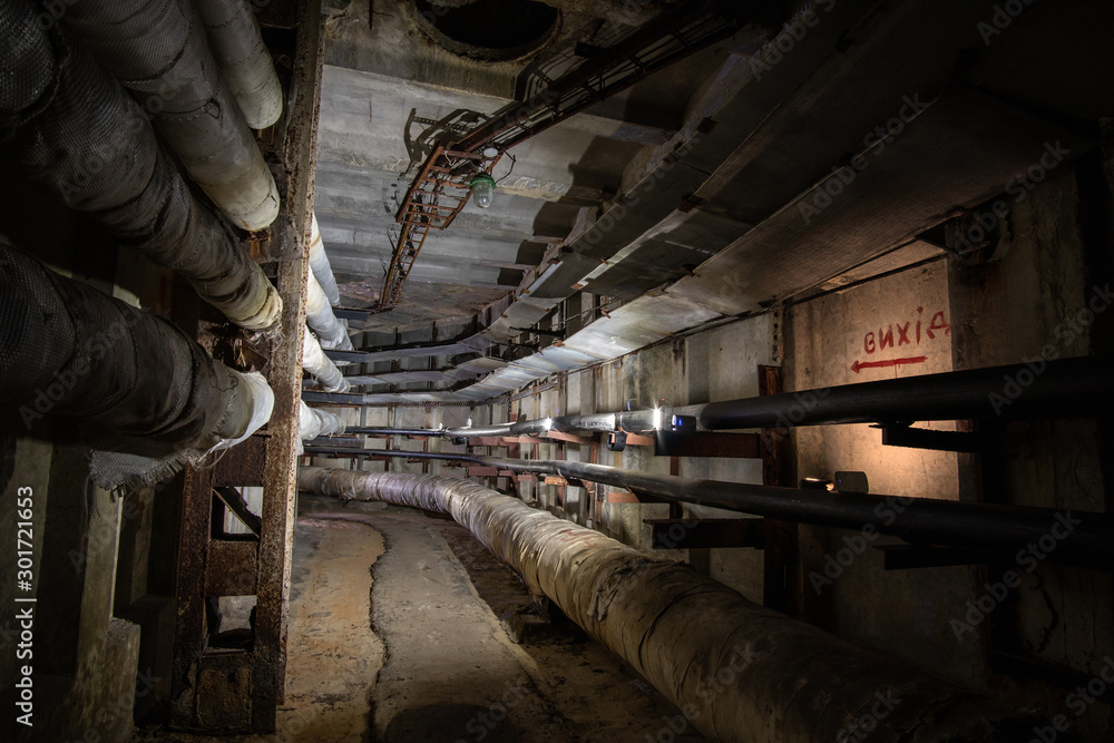 Underground concrete utility tunnel with pipes and wires. This tunnel ...