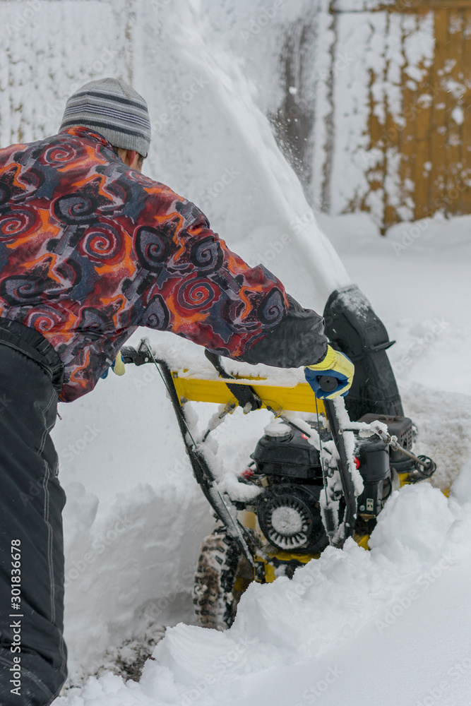 man operating snow blower to remove snow on driveway. Man using a ...