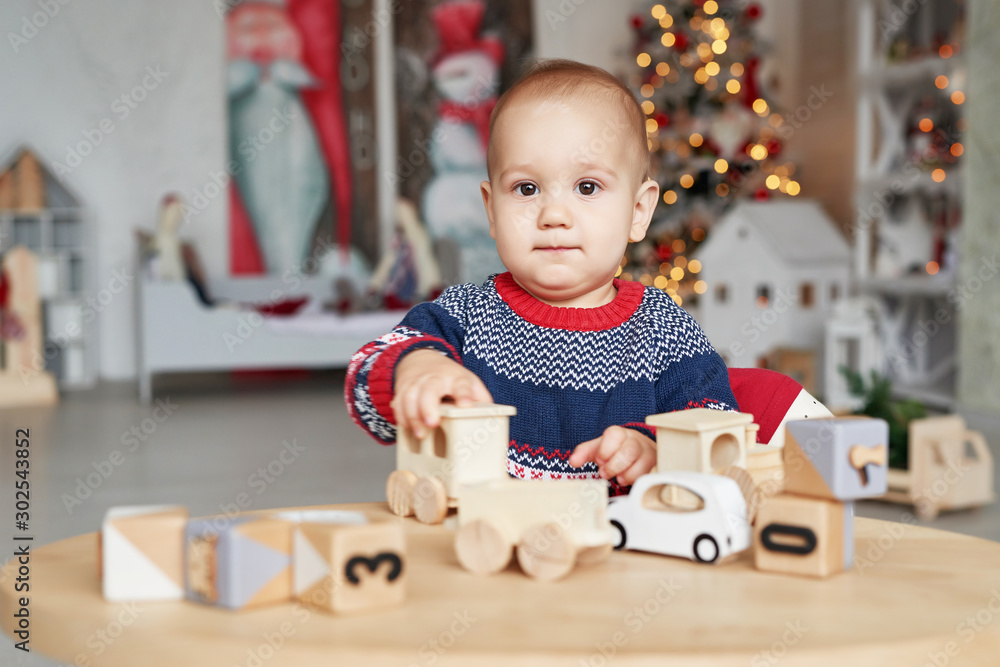 Cute little boy is playing with toy wooden train, toy car, pyramid and ...