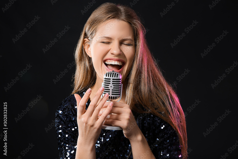 Beautiful young female singer with microphone on dark background Stock ...