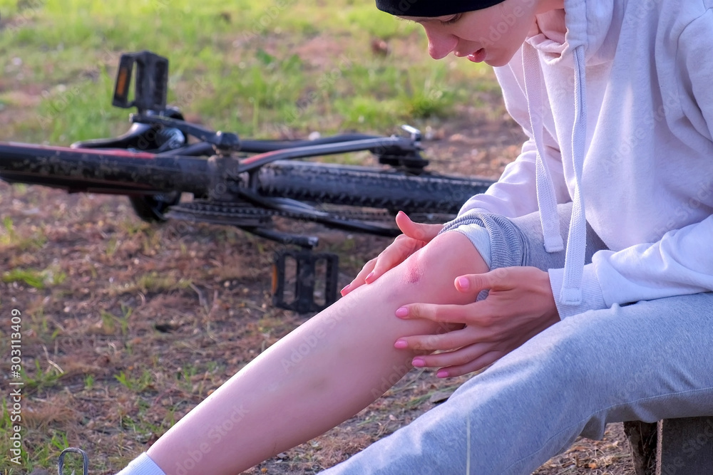 Photo Stock Woman examines pain wound on knees after falling off ...