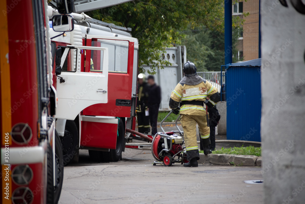 firefighter stands with his back near the fire engines, resting after ...