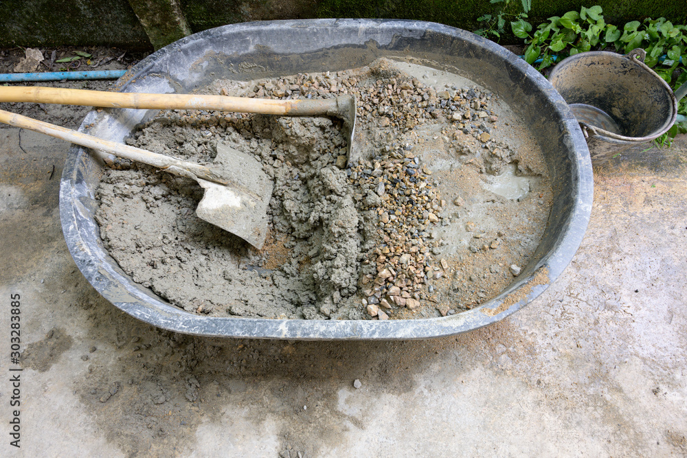 Mixed cement mortar with hoe leak inside big bucket on floor background ...