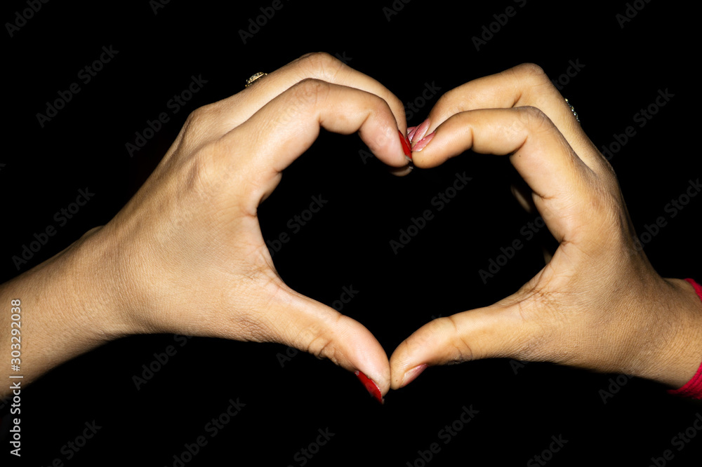 two women hands combined to form a sign of love on black background ...