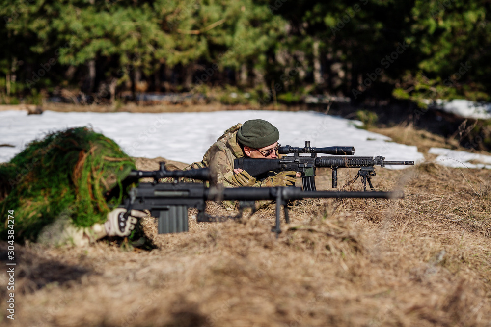sniper laying on the ground covered in a ghille suite tall grass and ...