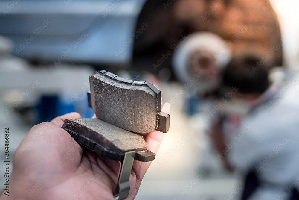 hand holding an uneven surface of a worn out disk brake pad in deep ...