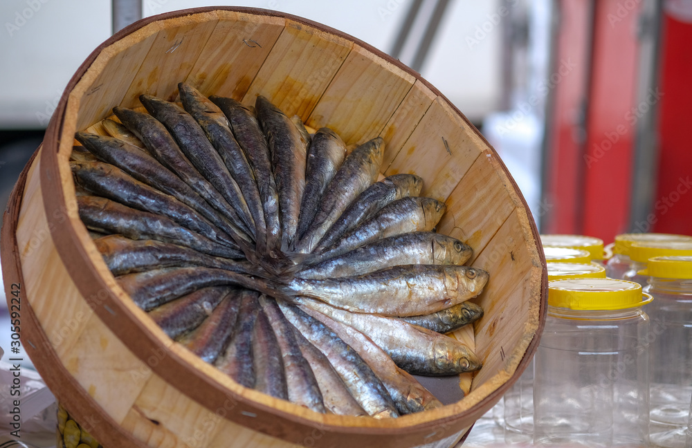 Freshly salted sardines in a round wooden box on a counter of farmer's ...