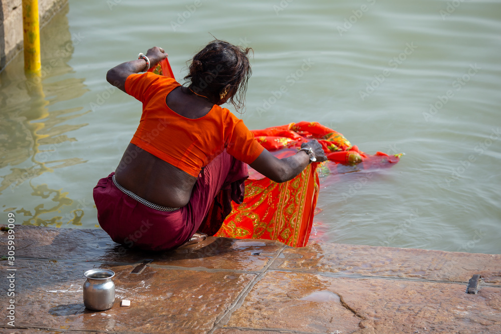 Life on the Ganges: Low caste untouchable indian woman washing a bright ...