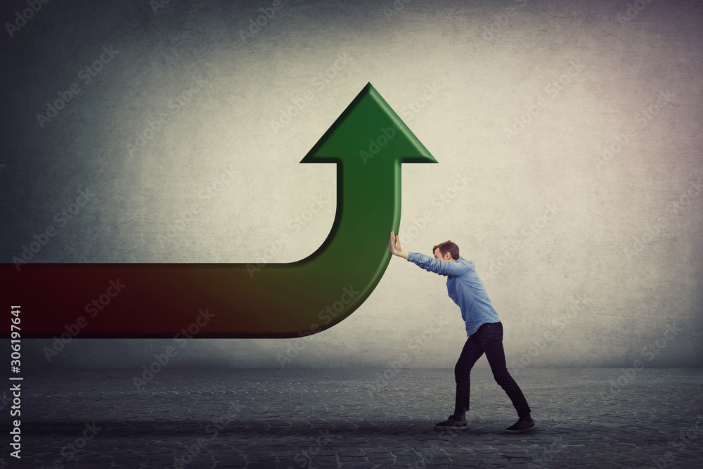 Determined man pushing an arrow to change the direction, bent ...