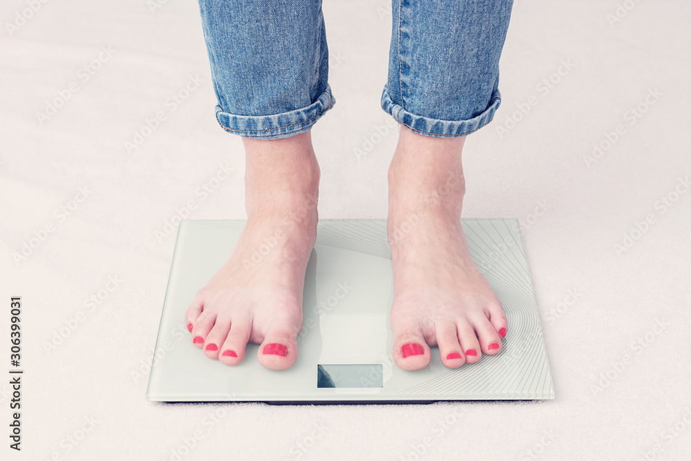Woman is weighed on scales, women's feet, cropped image, close up, top ...