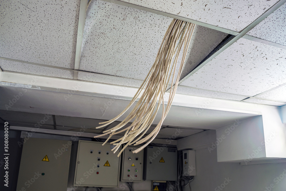 Communication cables drop out between the square panels of the false ...