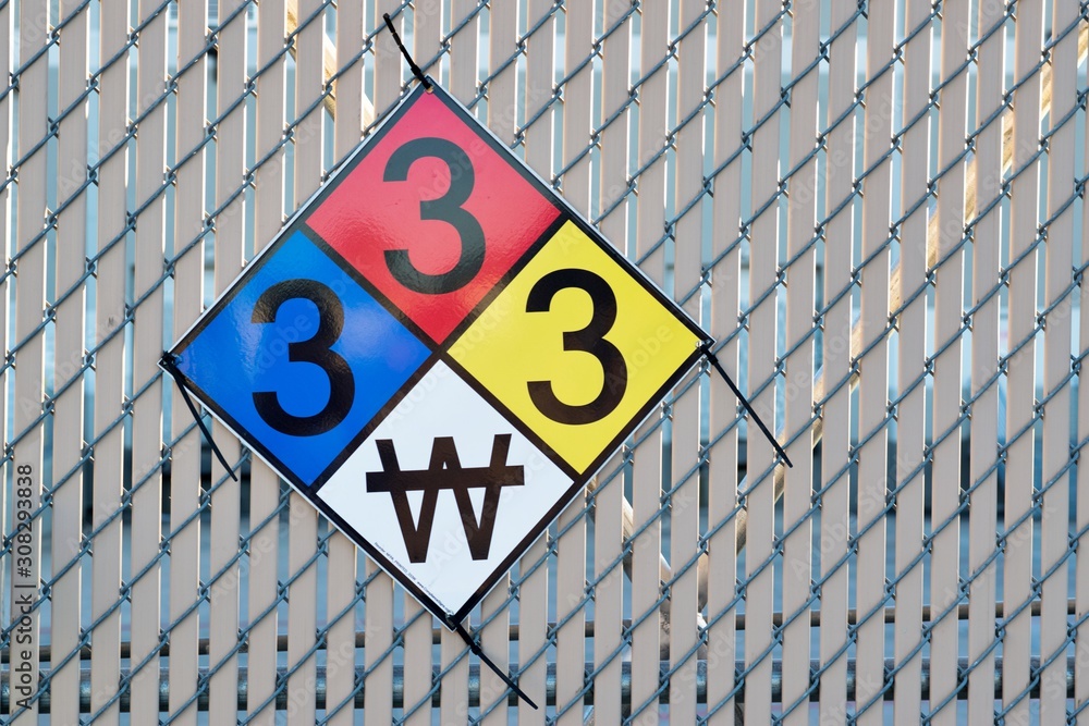 Hazardous Materials Classification Sign attached to a wire fence. The ...