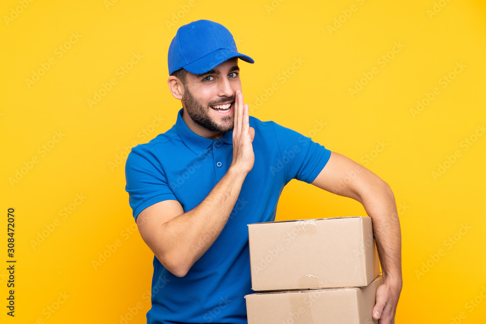 Delivery man over isolated yellow background whispering something Stock ...