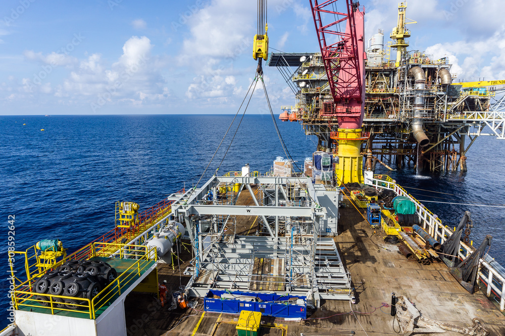 Offshore crane on board a construction work barge performing heavy ...