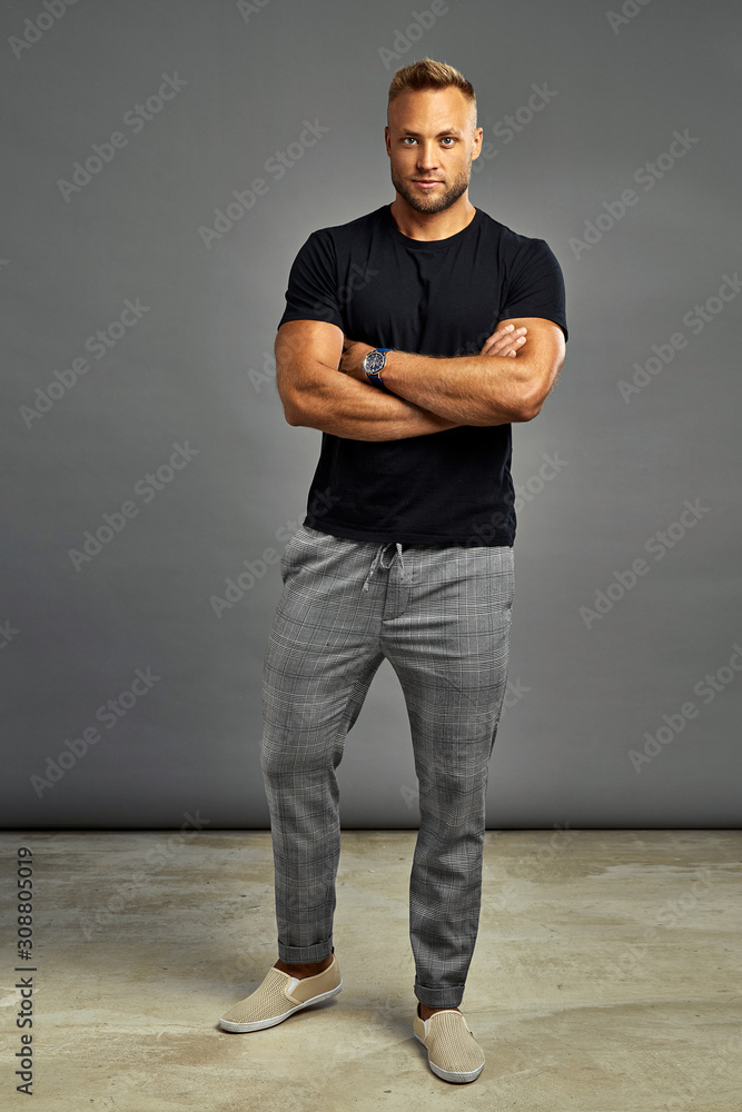 Handsome man posing with watch and looking at camera, isolated on gray ...