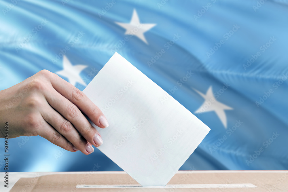 Micronesia election concept. Side view woman putting a ballot in a box ...