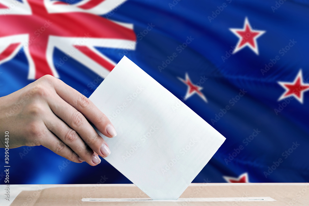 New Zealand election concept. Side view woman putting a ballot in a box ...