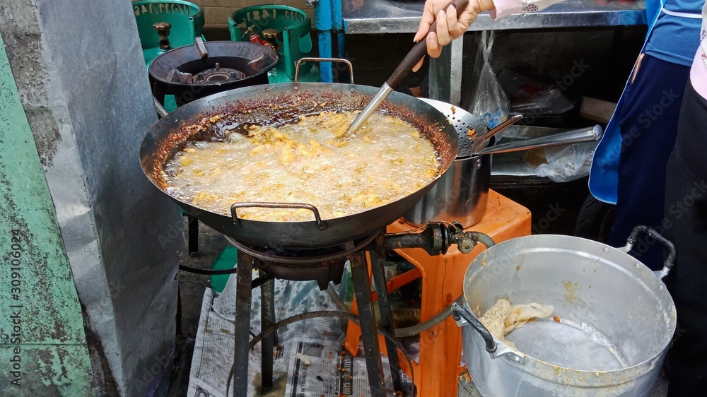 hand holding a flipper used for frying cooking a deep fried pork in pan ...