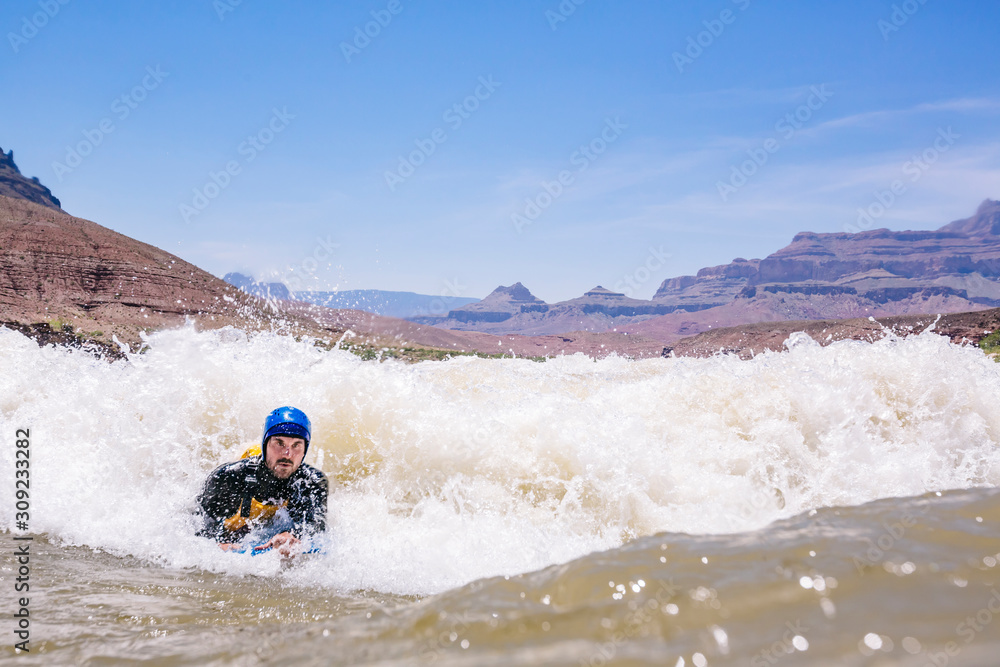 A man body boarding a wave in Basalt Rapid on the Colorado River, Grand ...