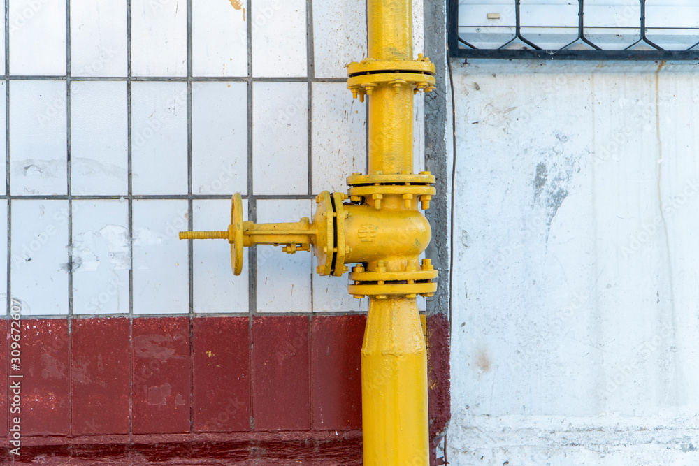 Big yellow gas valve on the pipe near balcony and wall with tiles ...