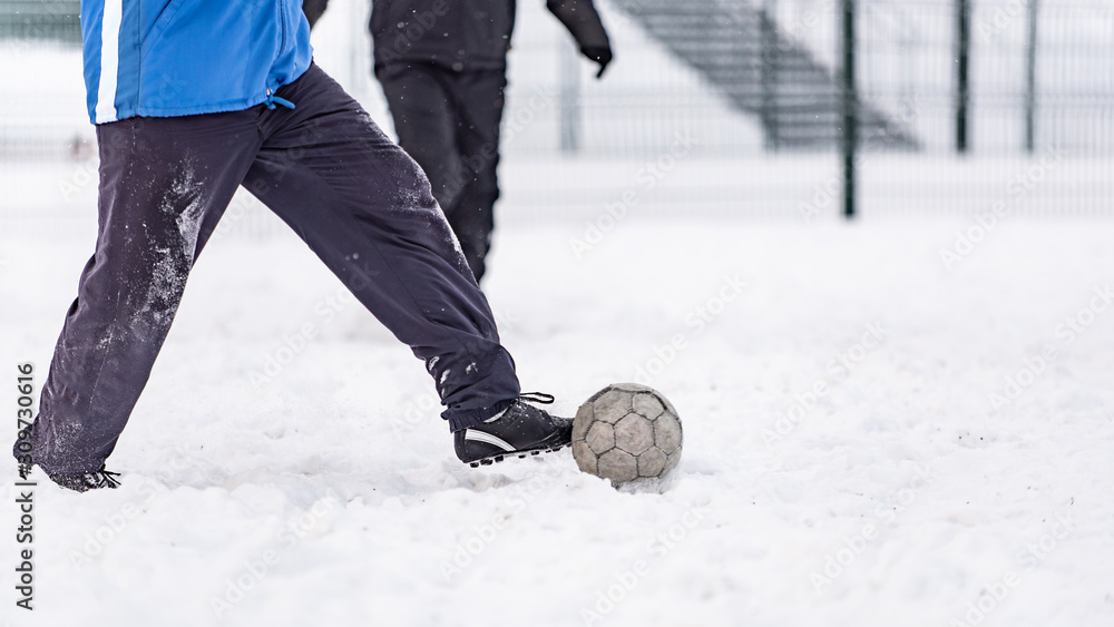 men play soccer in the snow with an old soccer ball. winter sports ...