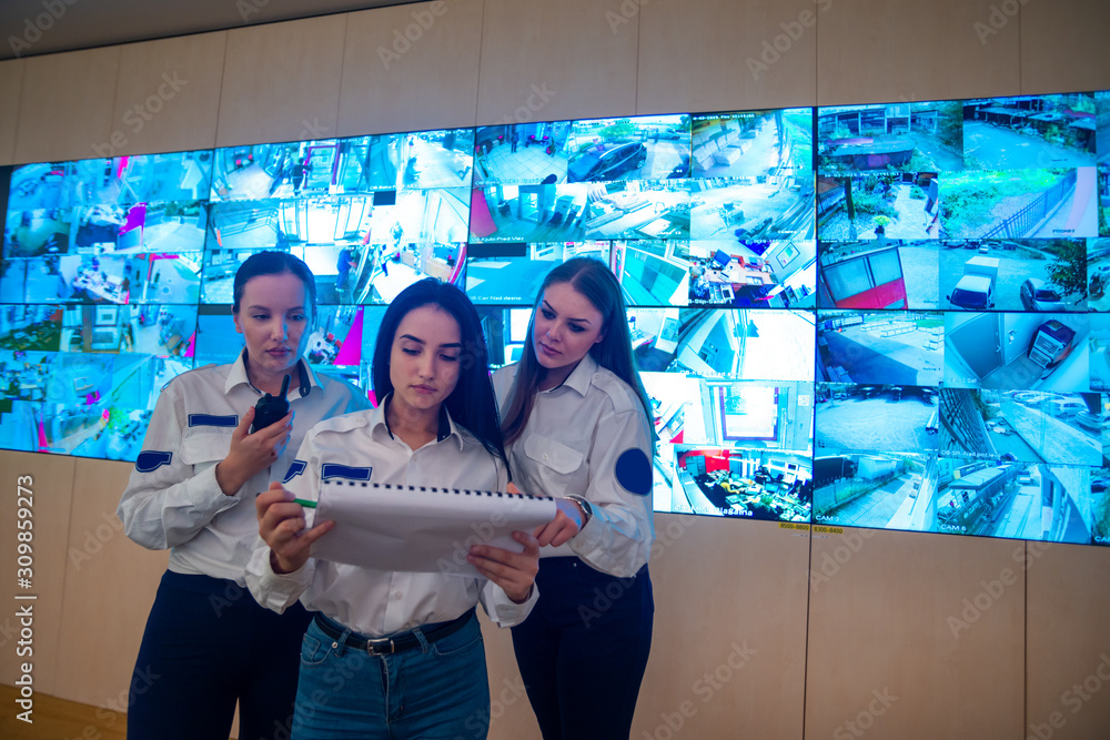 Security guards standing in front of a large CCTV monitor at the main ...