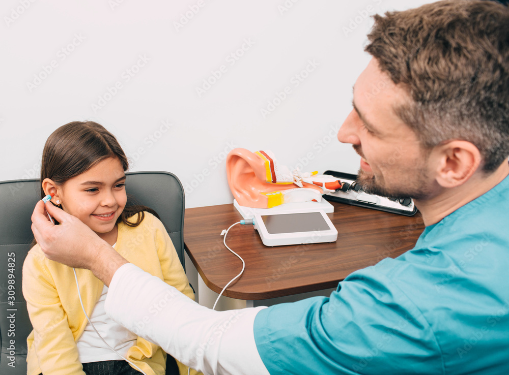 Audiologist check a child's ears.Mixed race girl having hearing test ...