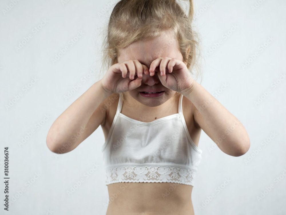 Little girl in a white top is crying. She has pain. Background ...