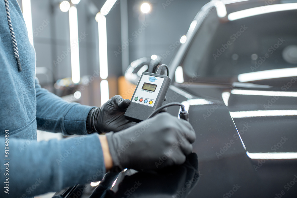 Inspector measuring paint cover thickness of the car body at the ...