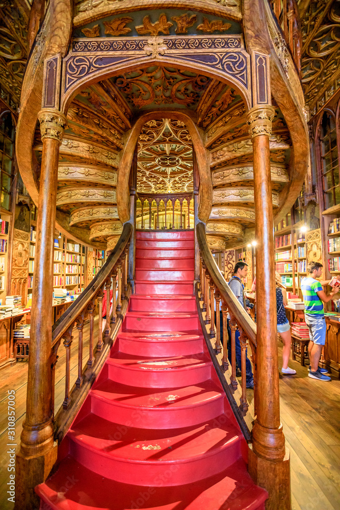 Oporto, Portugal - August 13, 2017: large wooden staircase with red steps inside Library Lello ...