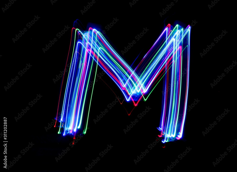 Long exposure photograph of a letter m in neon colour in an abstract ...
