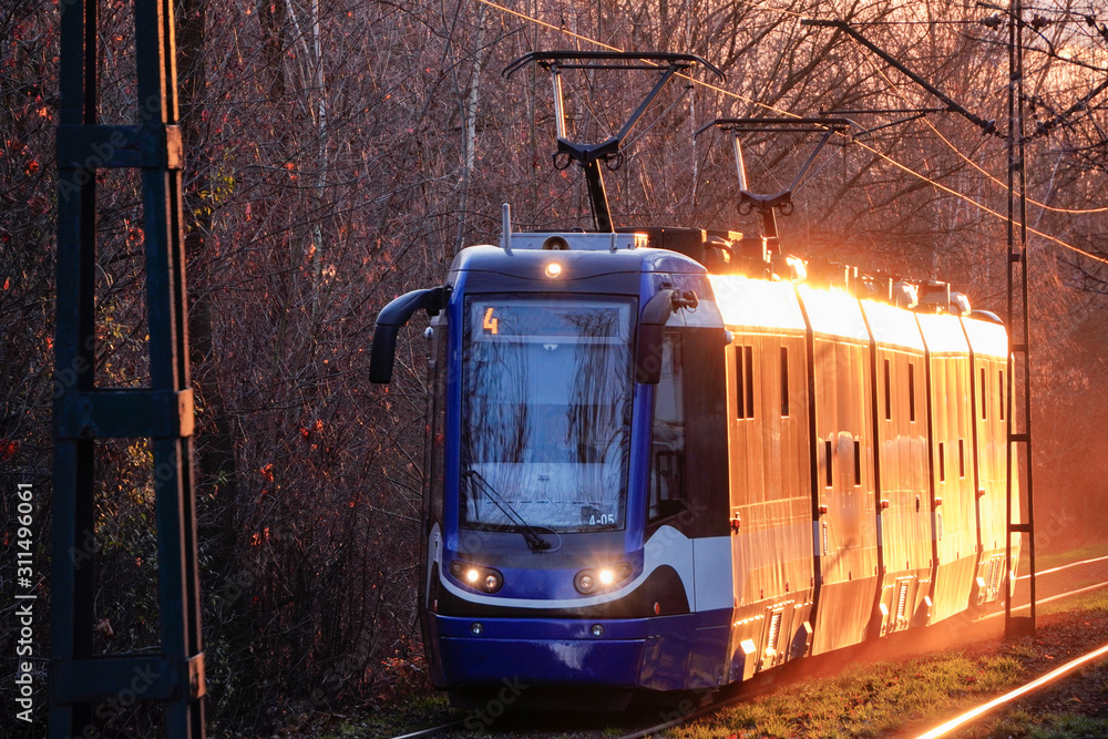 city trams in rays of the sunset soft bright back-light sun, glare on ...