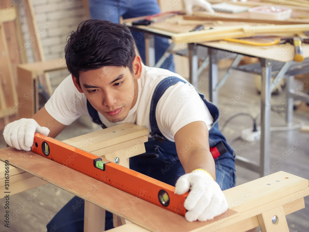 Asian young male carpenter using Water Level Gauge Ruler in the room ...