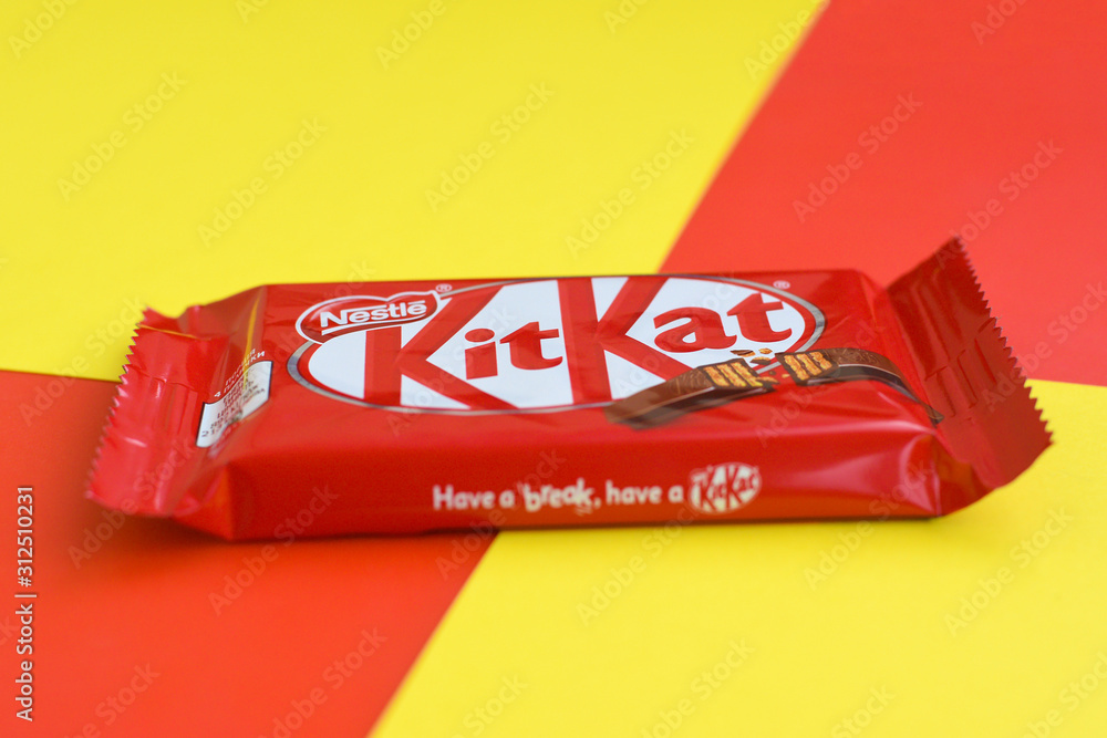 Kit Kat chocolate bars in red wrapping lies on yellow and red ...