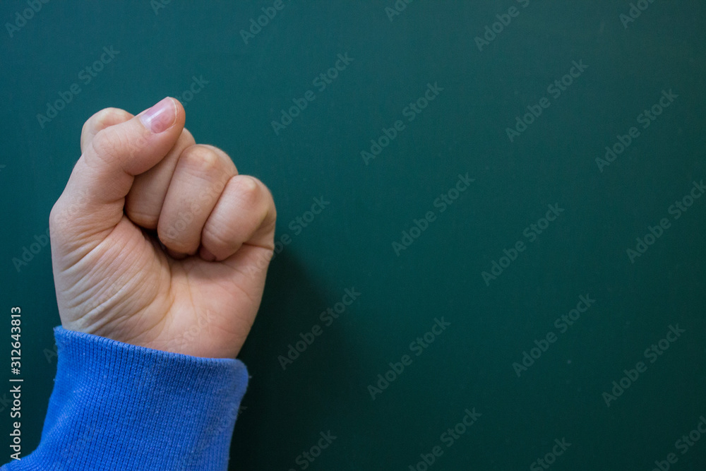 Hand in a fist close up on the background of the school green Board ...