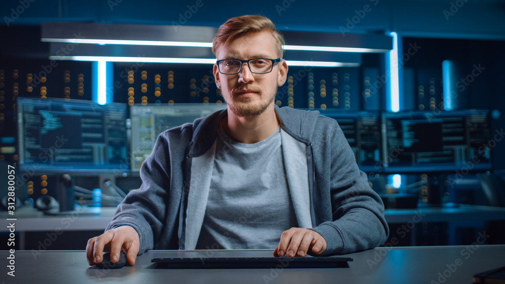 Portrait of Software Developer / Hacker Wearing Glasses Sitting at His Desk and Working on ...