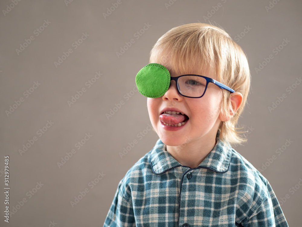 Portrait of funny child in new glasses with green spot to correct ...