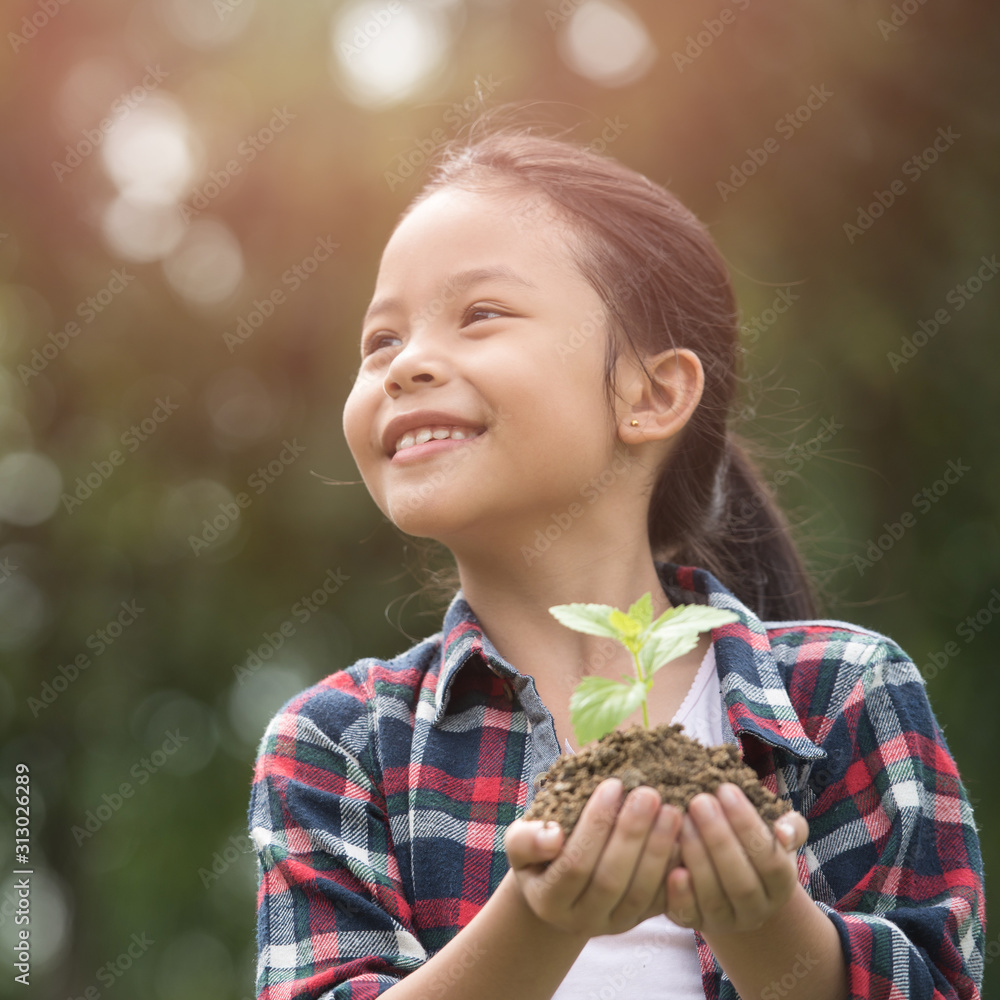 Kid holding young plant in hands against spring green background ...