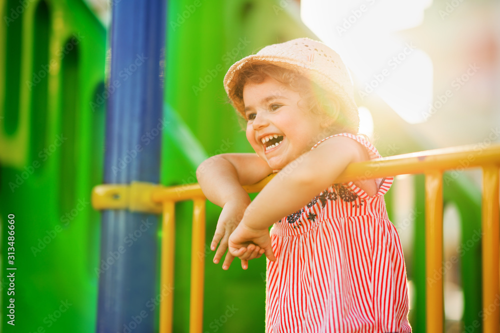 Little cute girl playing in playground an wearing hat. Concept play in ...