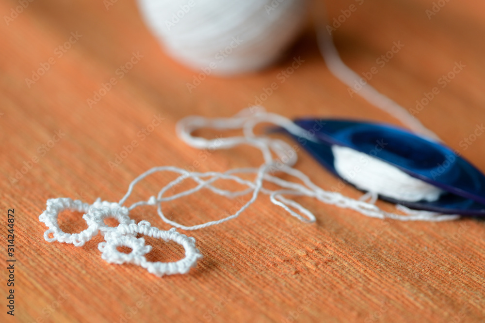 Tatting lace in the manufacturing process. Fragment of lace and shuttle ...
