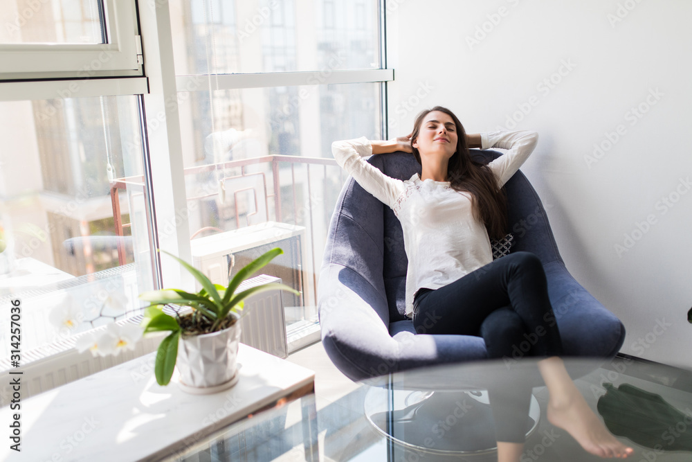 Relaxing woman sitting comfortable in sofa lounge chair at home Stock ...