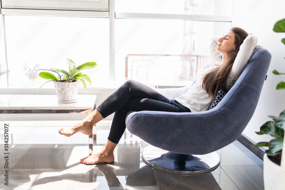 Relaxing woman sitting comfortable in sofa lounge chair at home Stock ...